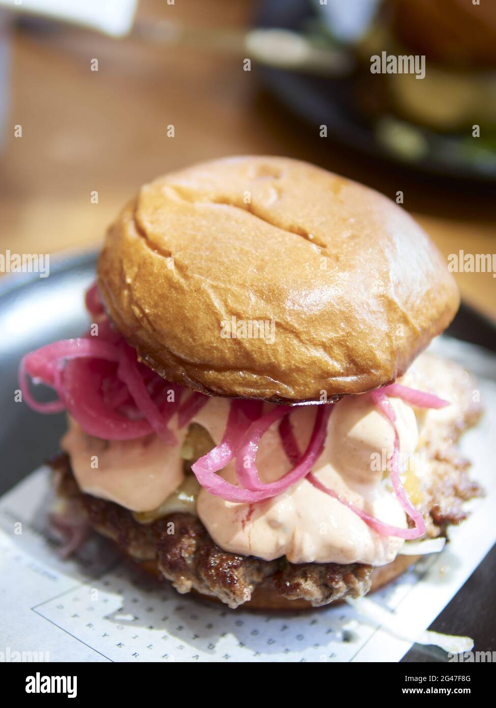 Vertical selective focus shot of a fat, juicy burger with onions and ...