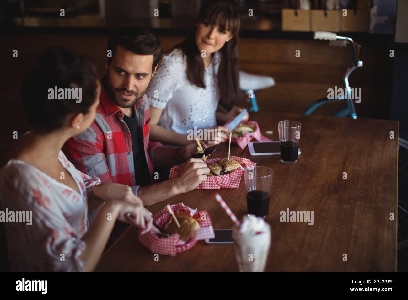 Friends having burger together Stock Photo - Alamy