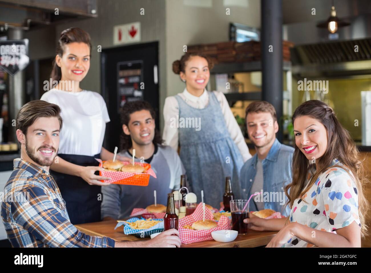 Group of friends with waitress in restaurant Stock Photo - Alamy