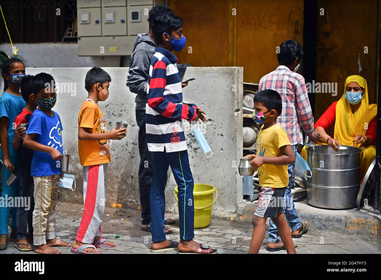 A woman serves milk to children in a slum. The marginalized communities ...