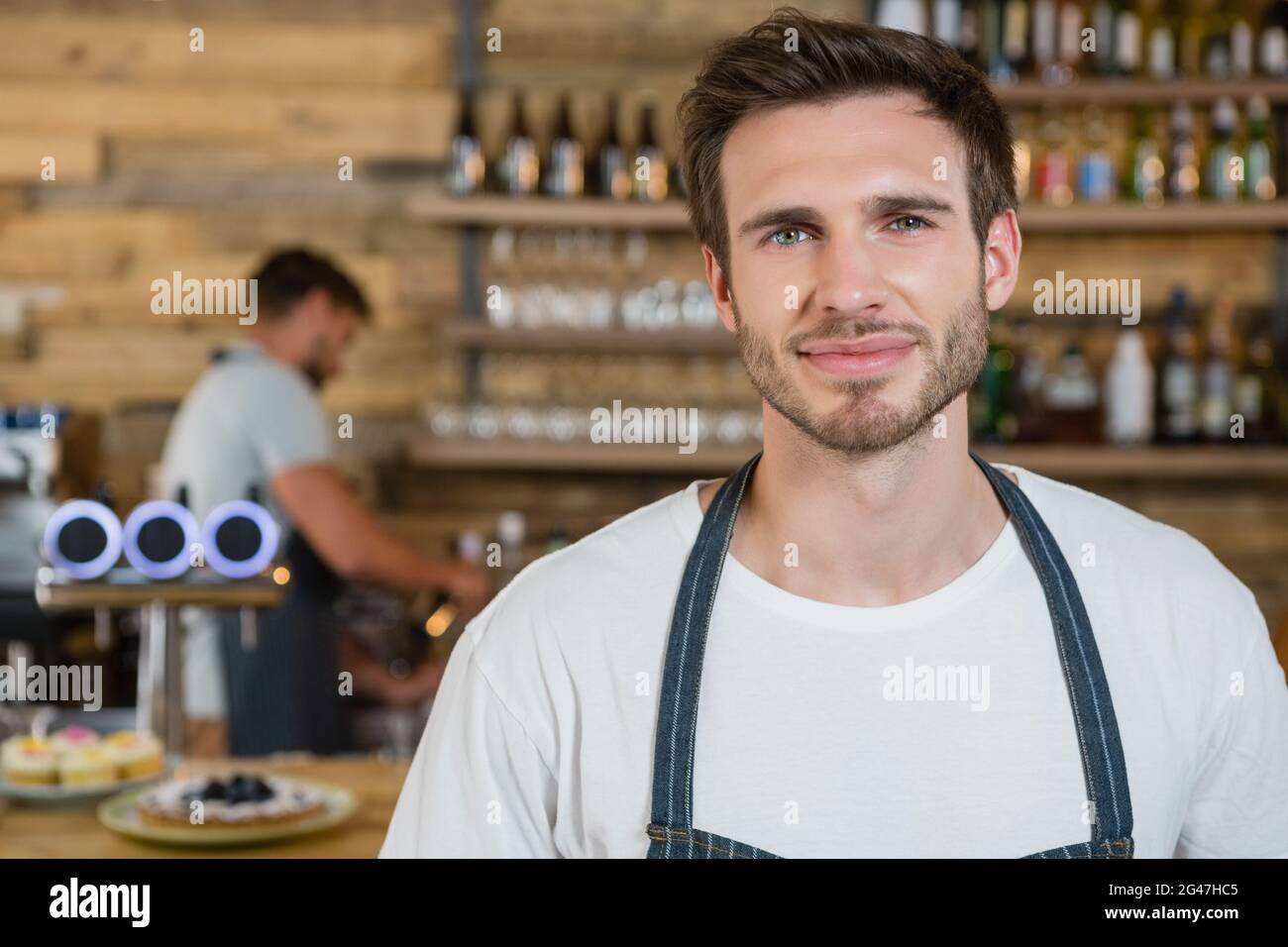 Portrait of waiter standing behind the counter Stock Photo - Alamy