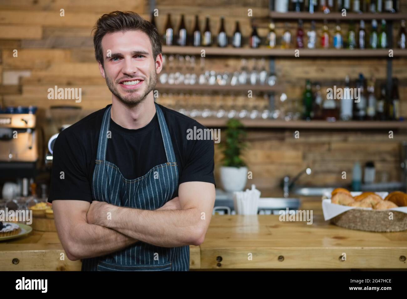 Portrait of smiling waiter standing with arms crossed at counter Stock ...