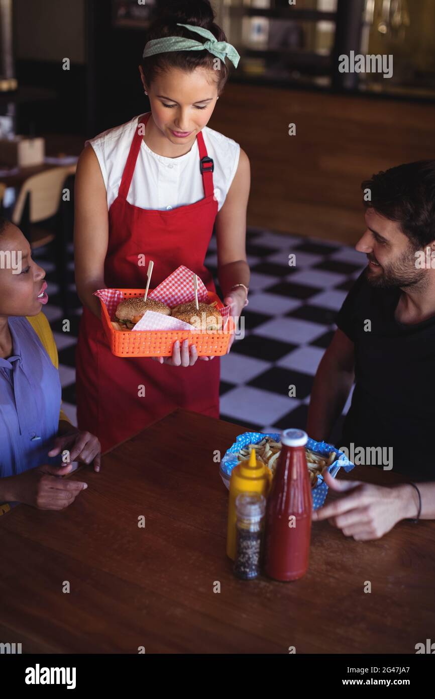 Waitress serving burger and french fries to customer Stock Photo - Alamy