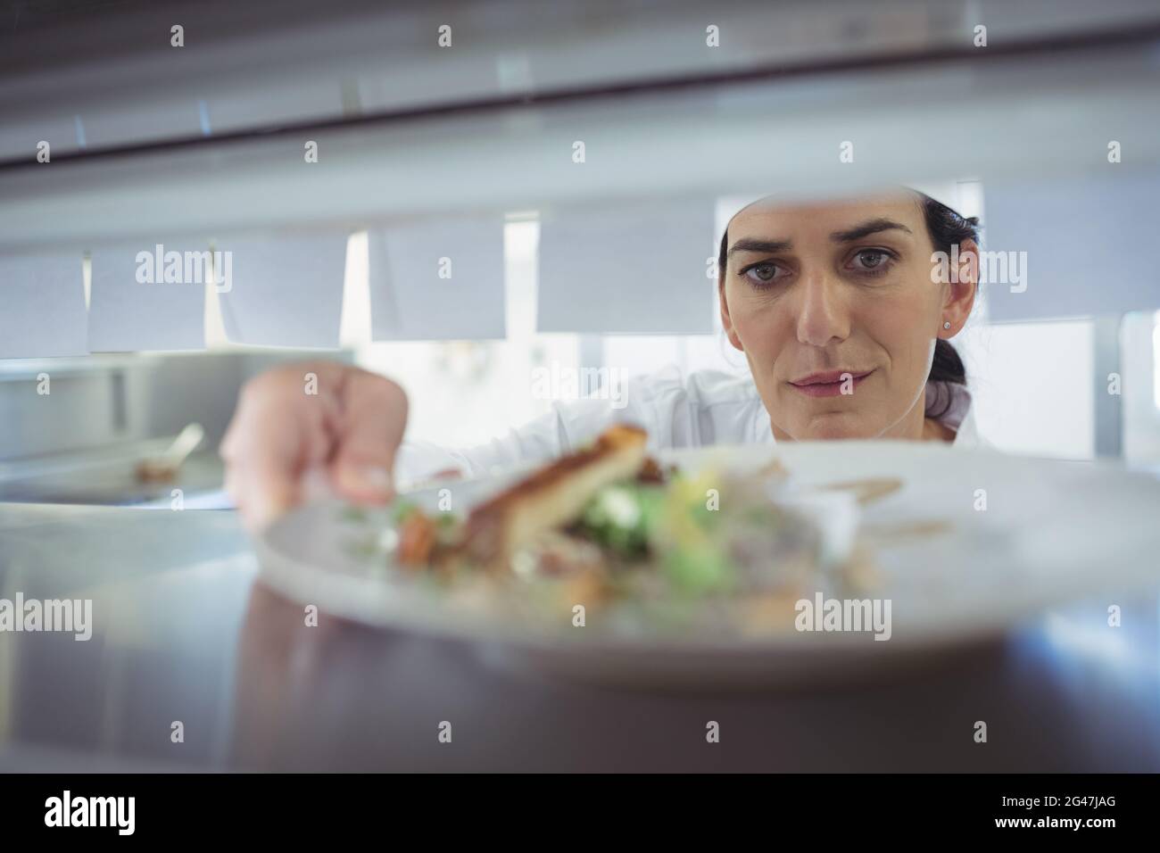 Waitress taking food dishes from order station Stock Photo - Alamy