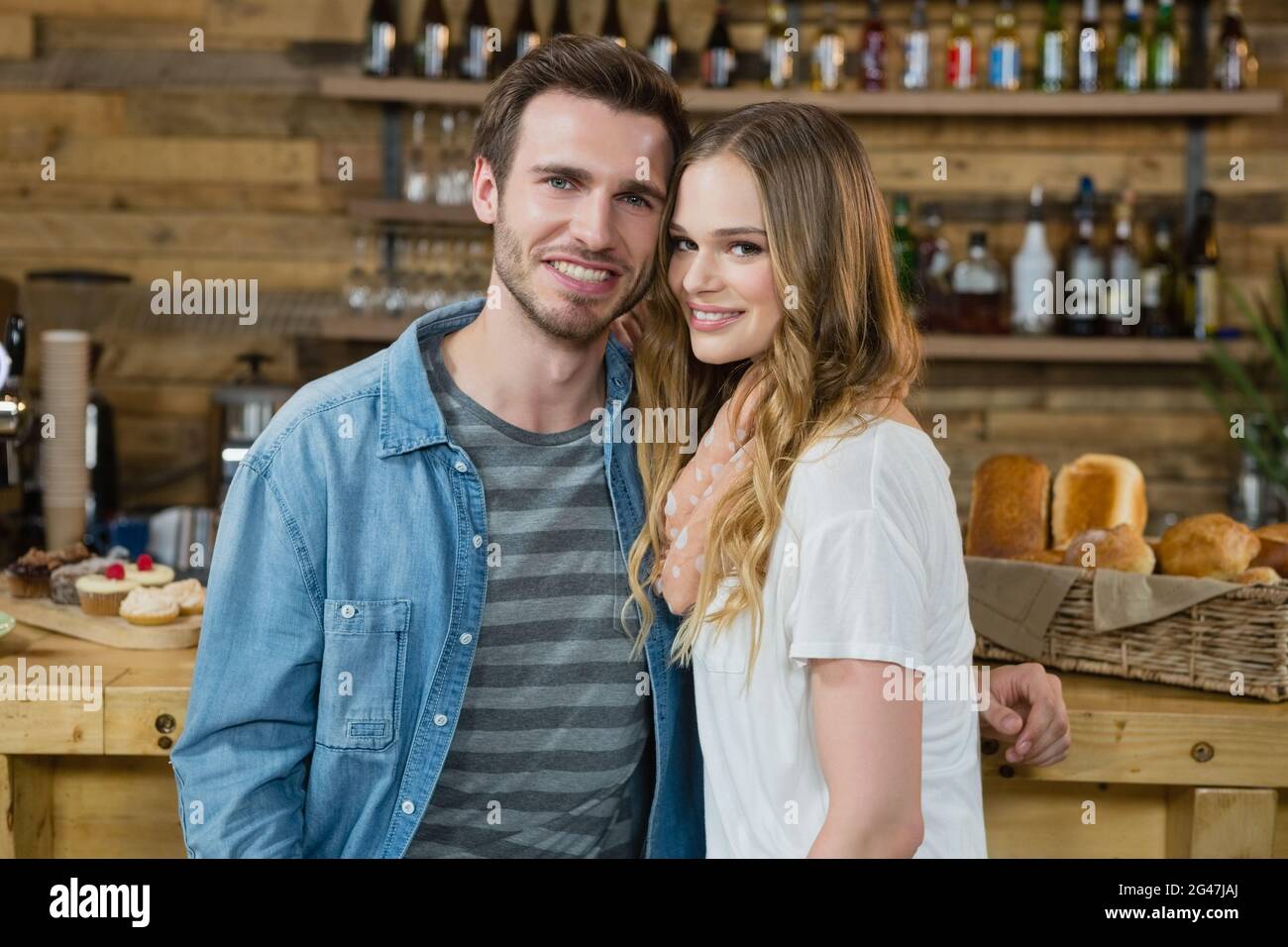Portrait of smiling couple standing behind the counter Stock Photo - Alamy