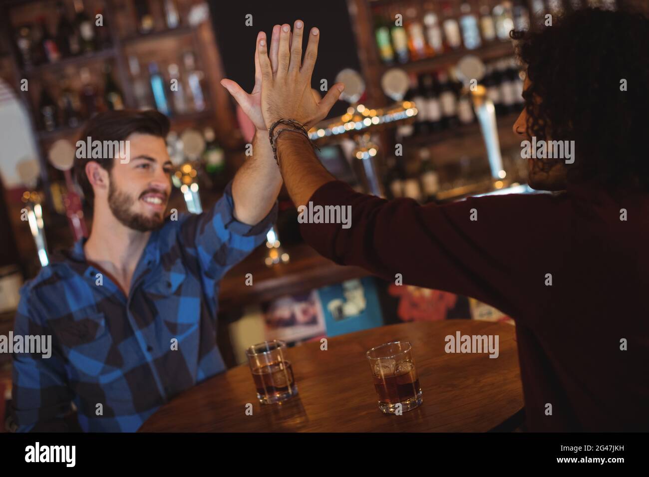 Friends giving high five while having drink Stock Photo - Alamy