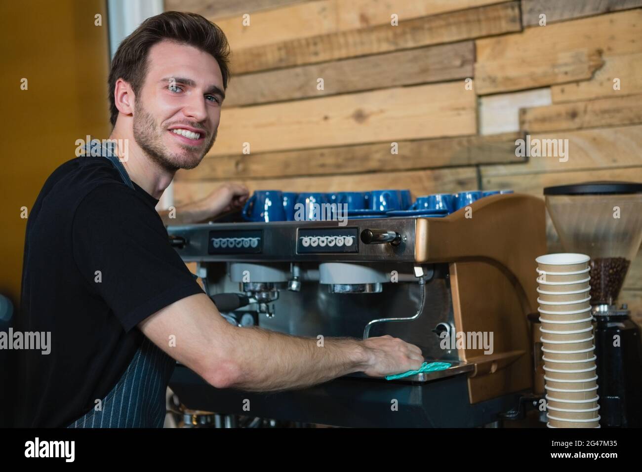 Portrait of smiling waiter cleaning coffee machine at counter Stock ...