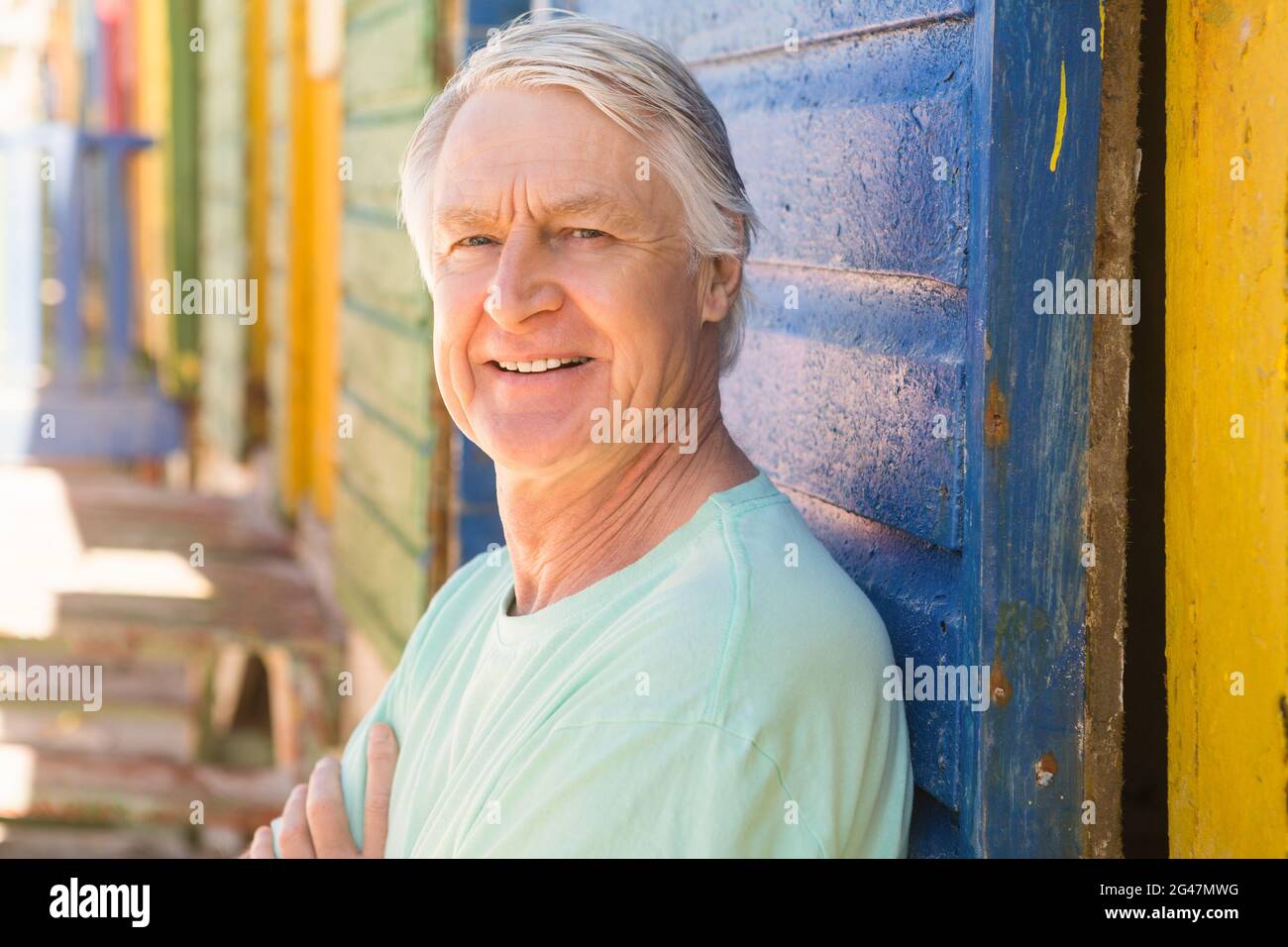 Portrait of smiling senior man standing by wall Stock Photo - Alamy
