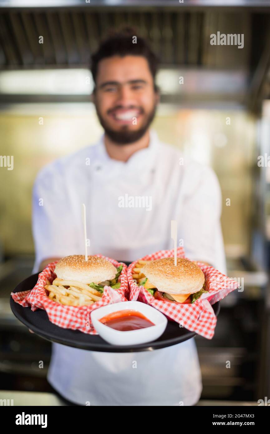 Chef holding burgers in plate at commercial kitchenc Stock Photo - Alamy