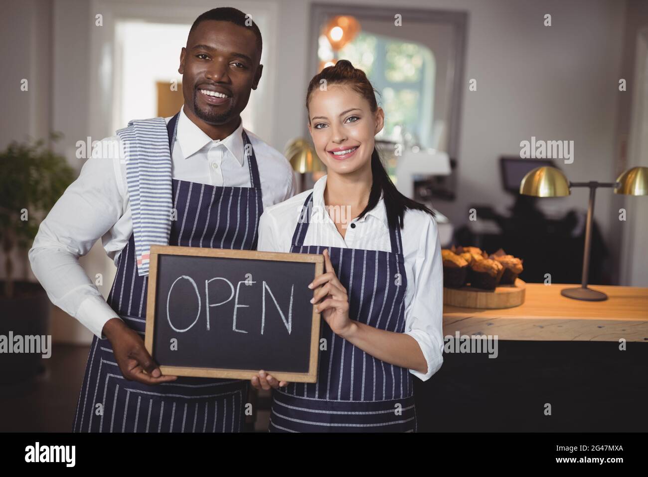 Smiling waiter and waitress showing chalkboard with open sign Stock ...