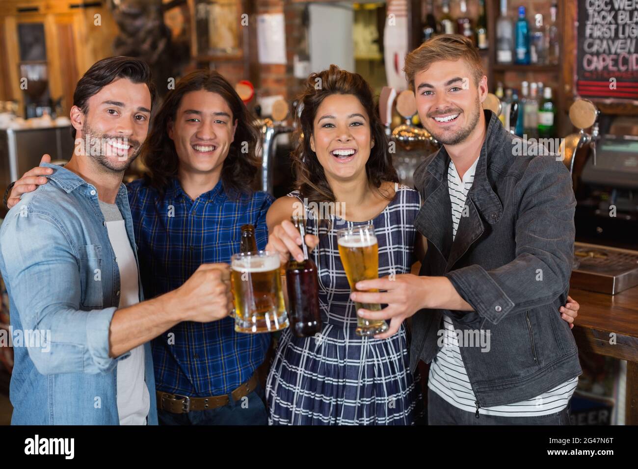 Portrait of friends tossing beer glasses and bottles in pub Stock Photo ...