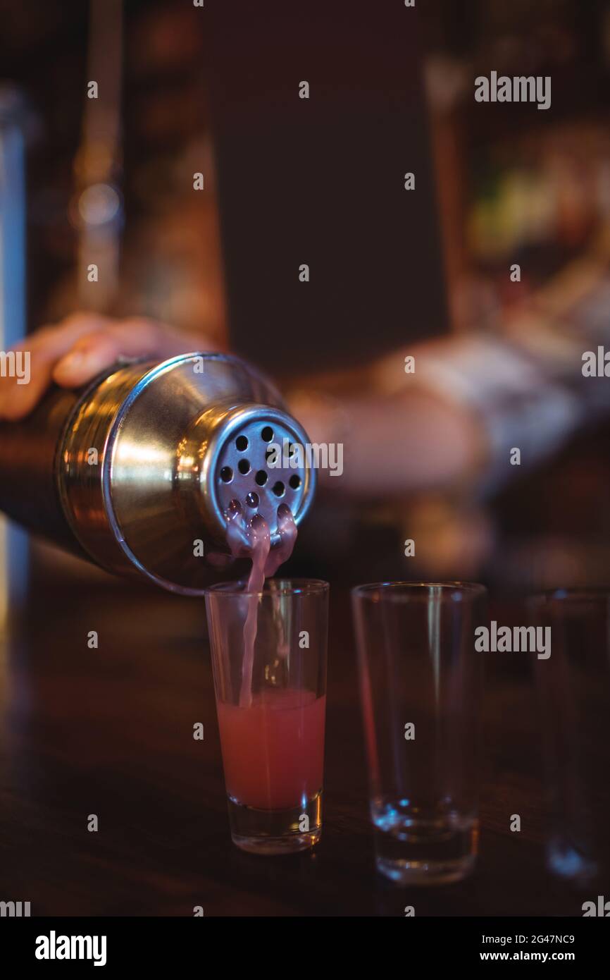 Waiter pouring cocktail drink into shot glasses at counter Stock Photo ...
