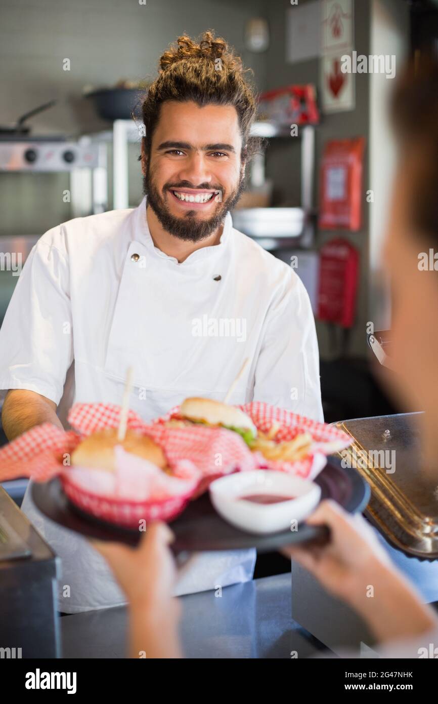 Happy chef giving burgers to waitress Stock Photo - Alamy