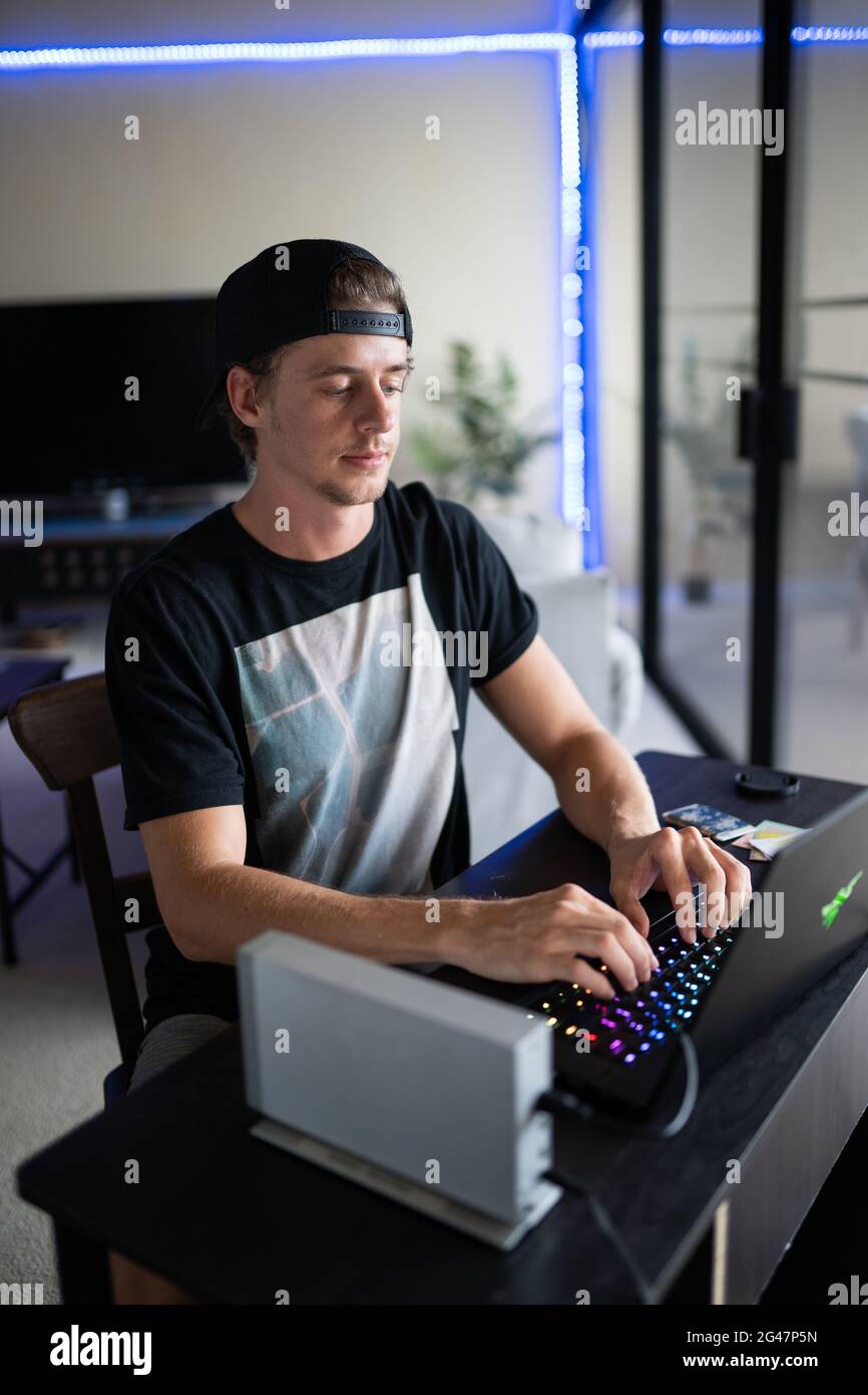 Vertical shot of an American guy with a cap, sitting at his desk and ...