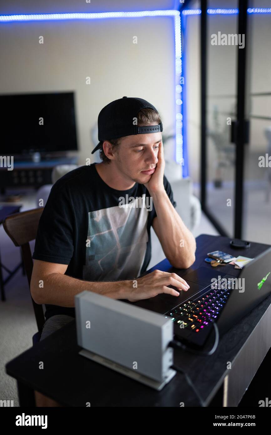 Vertical shot of an American guy sitting at his desk, playing boring ...