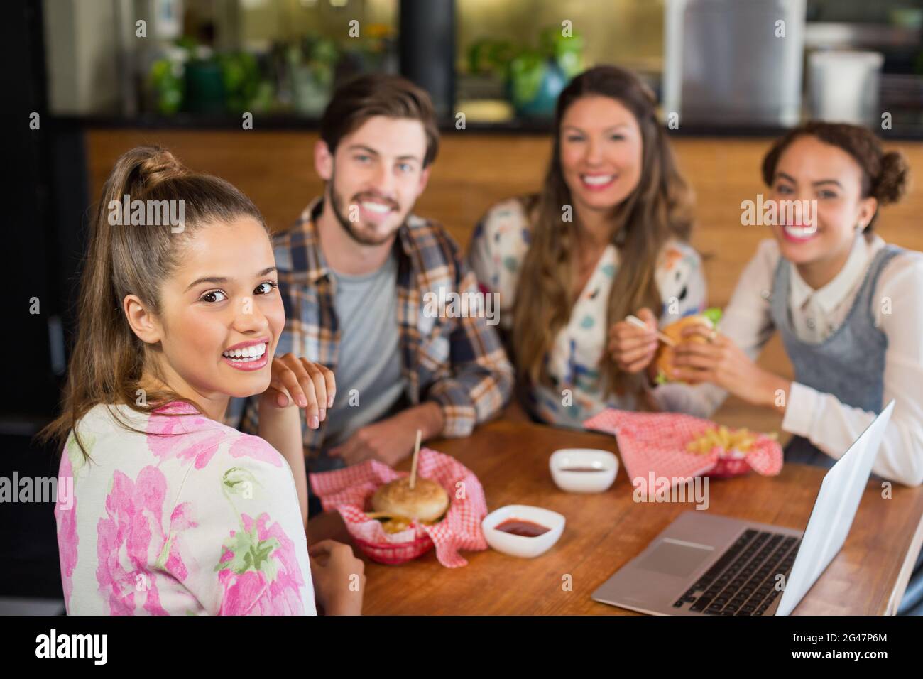 Happy friends having burger in restaurant Stock Photo - Alamy