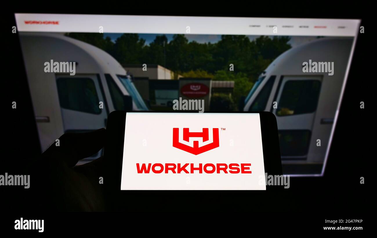 Person holding mobile phone with logo of US electric vehicle company ...