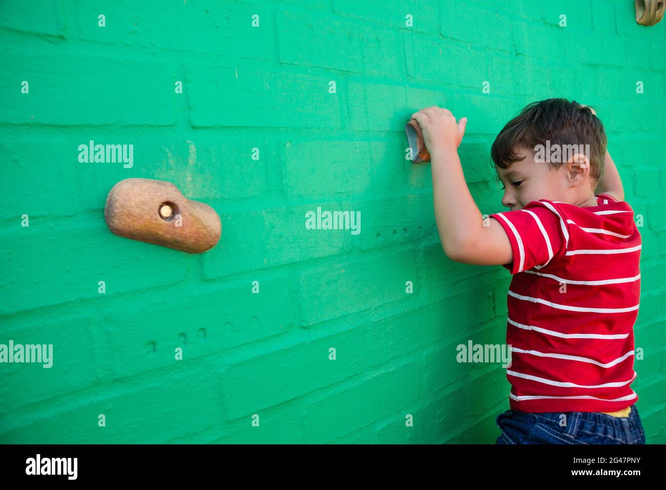 Rear view of boy climbing wall at playground Stock Photo - Alamy