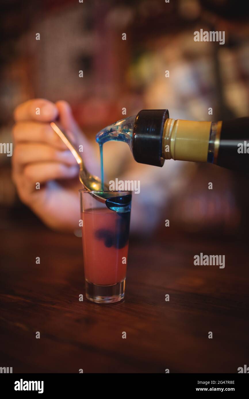 Waiter pouring cocktail drink into shot glasses at counter Stock Photo ...