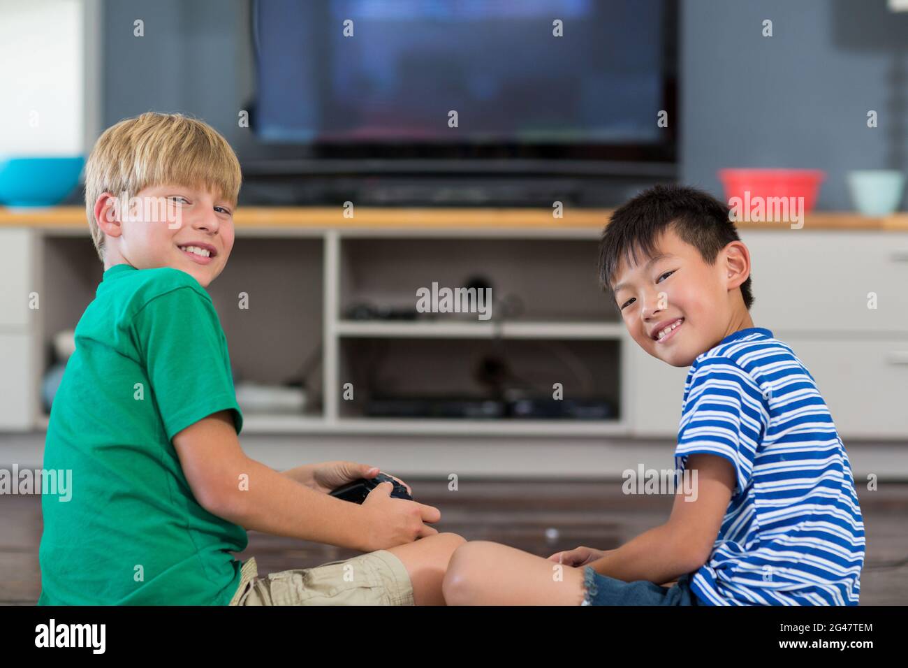 Happy siblings playing video games in living room Stock Photo - Alamy