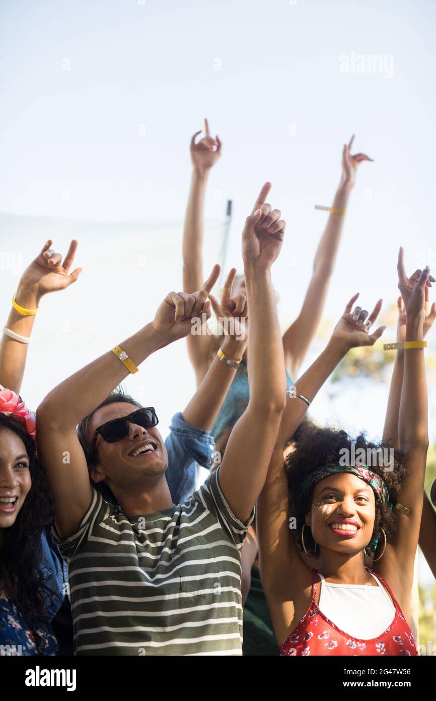 Happy fans dancing with arms raised during music festival Stock Photo ...