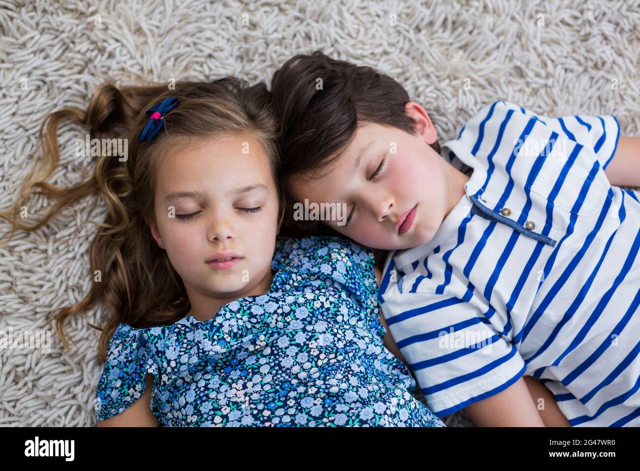 Siblings sleeping on rug in living room Stock Photo - Alamy