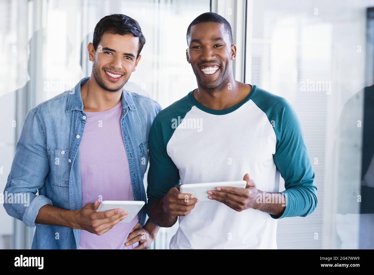 Portrait of smiling male colleagues using digital tablets Stock Photo ...