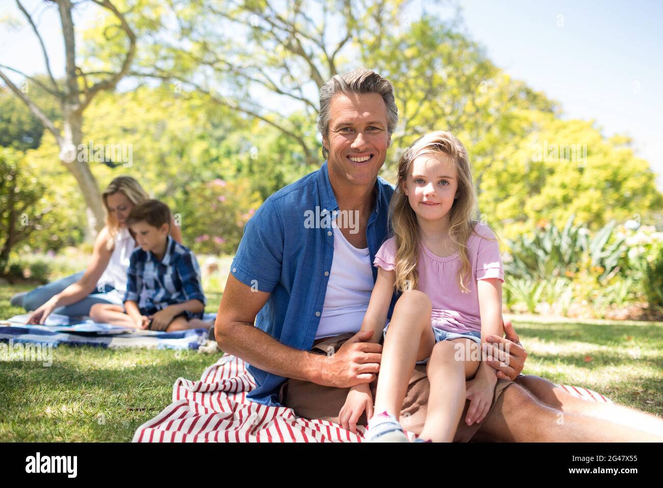 Daughter sitting on fathers lap in park Stock Photo - Alamy