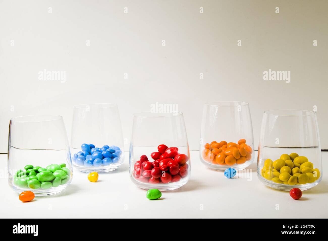 Closeup of glasses with colorful sweet candies isolated on white ...