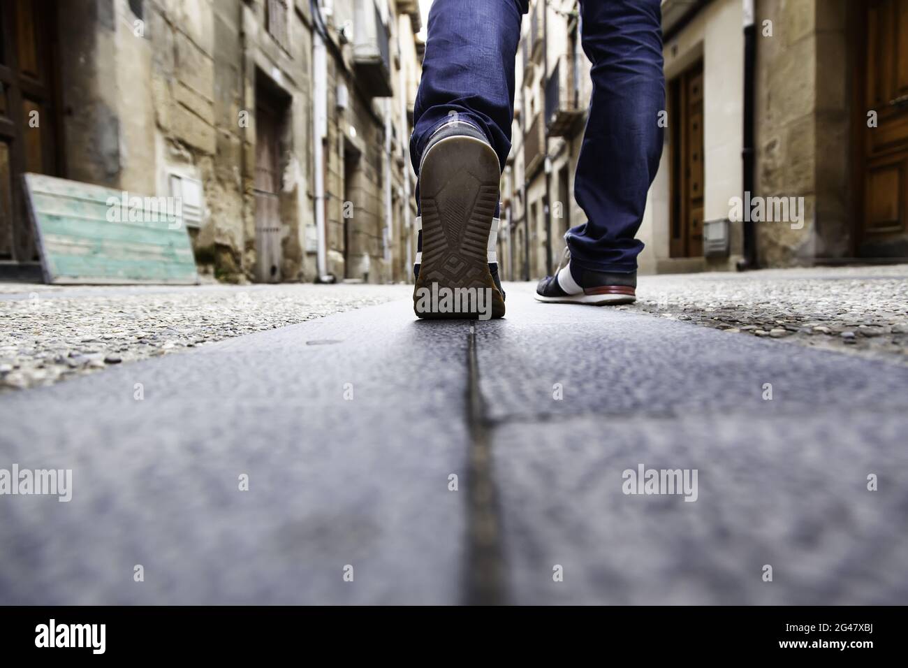 Detail of person walking down an old street Stock Photo - Alamy