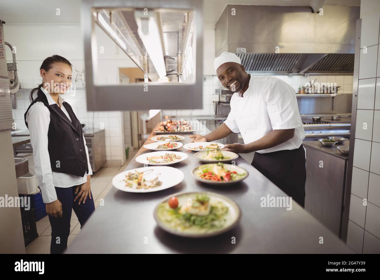 Chef and waitress showing food dishes to the camera Stock Photo - Alamy