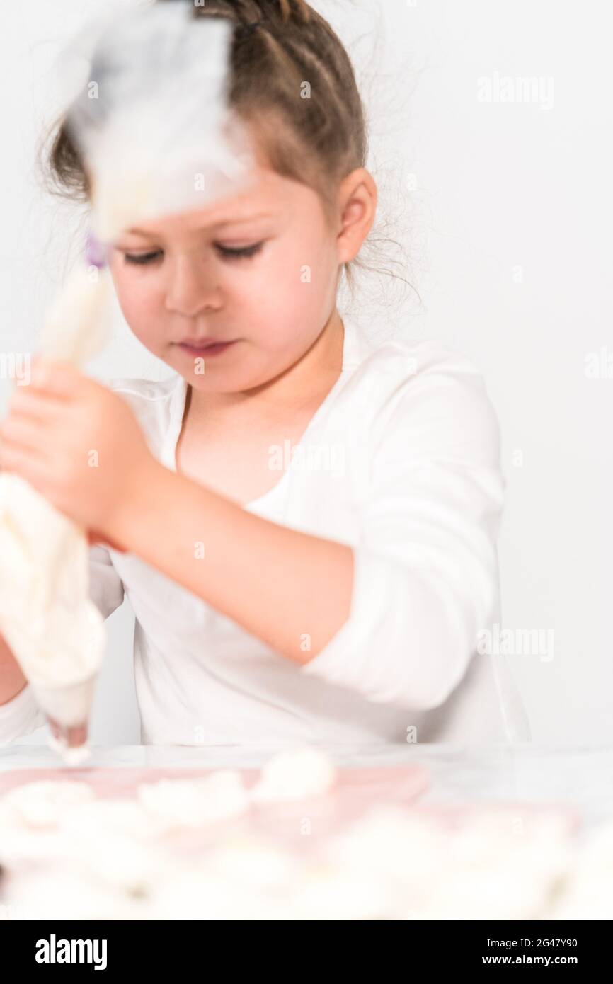 Little girl practicing piping Italian buttercream frosting Stock Photo ...