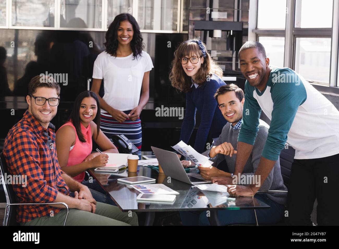 Portrait of smiling colleagues at desk Stock Photo - Alamy