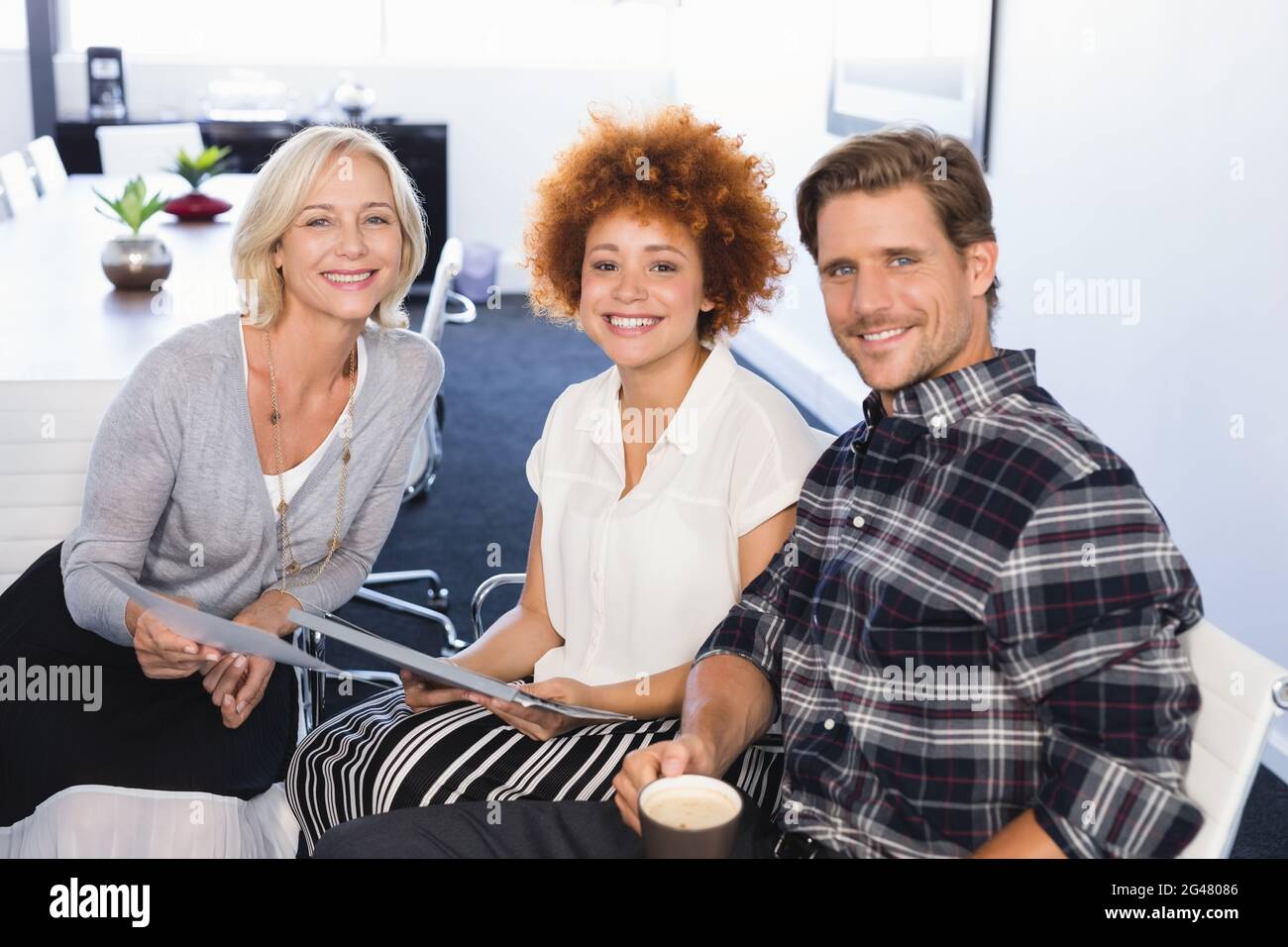 Portrait of happy business people sitting on chairs Stock Photo - Alamy