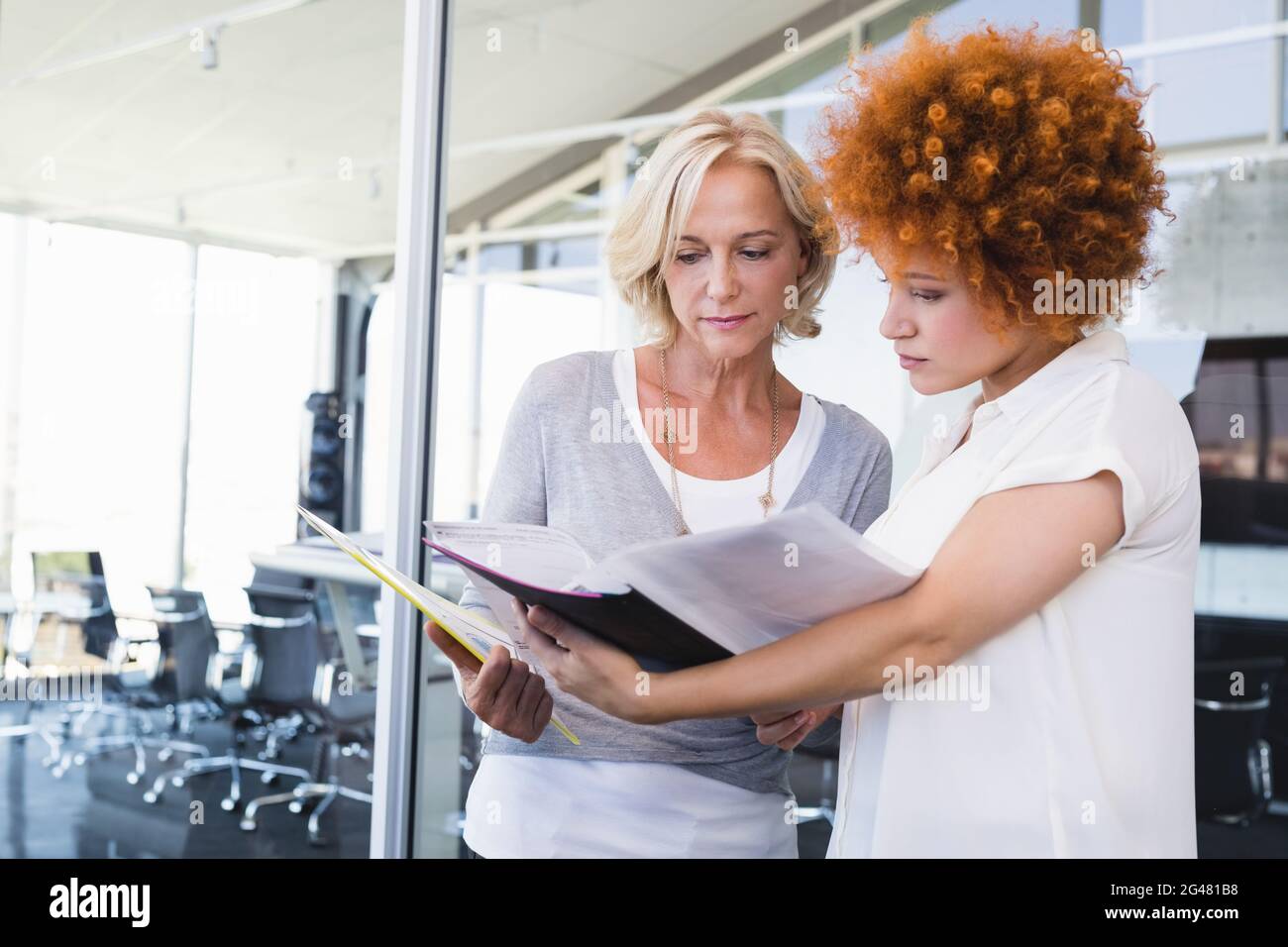 Businesswomen discussing over file in balcony Stock Photo - Alamy