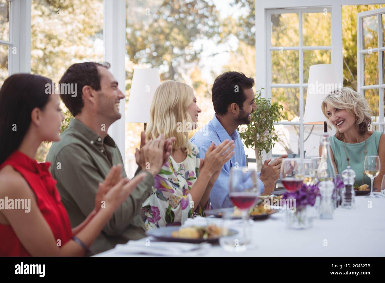 Group of friends interacting with each other while having meal together ...