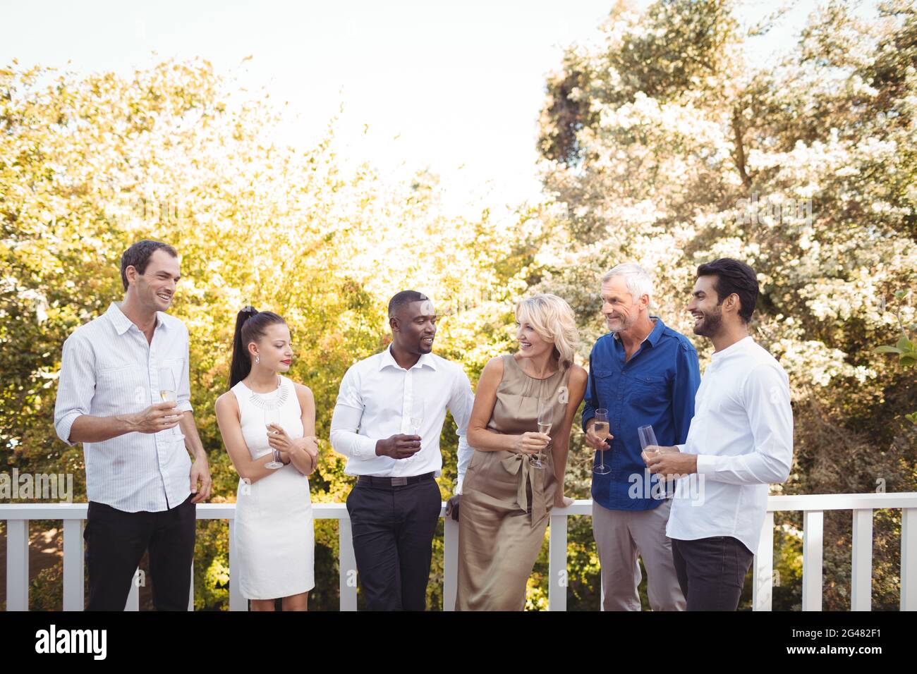 Friends interacting with each other while having champagne in balcony ...