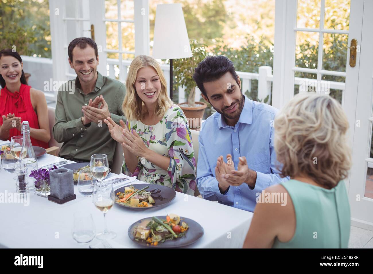 Group of friends interacting with each other while having meal together ...