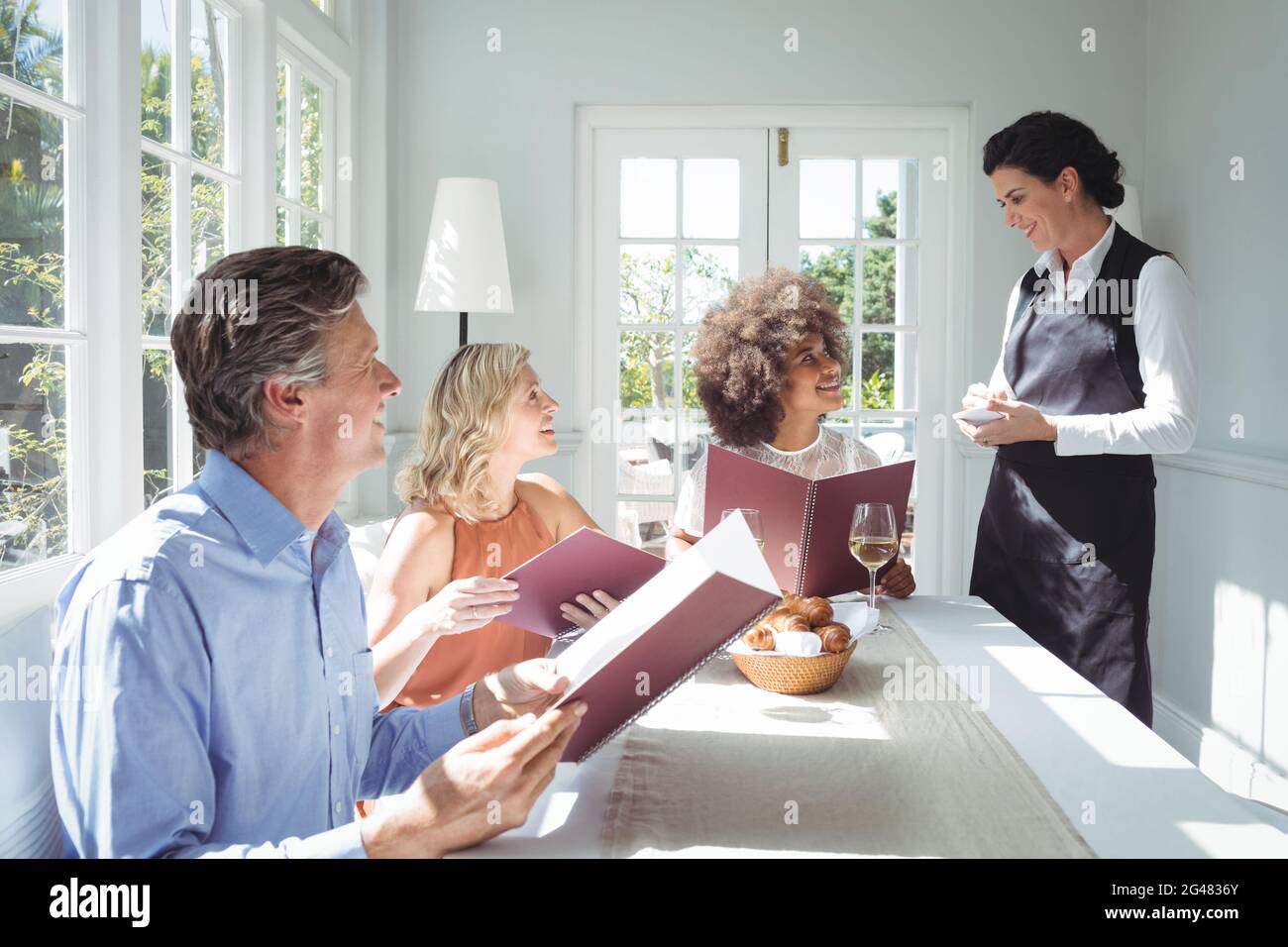 Friends placing order to waitress Stock Photo - Alamy