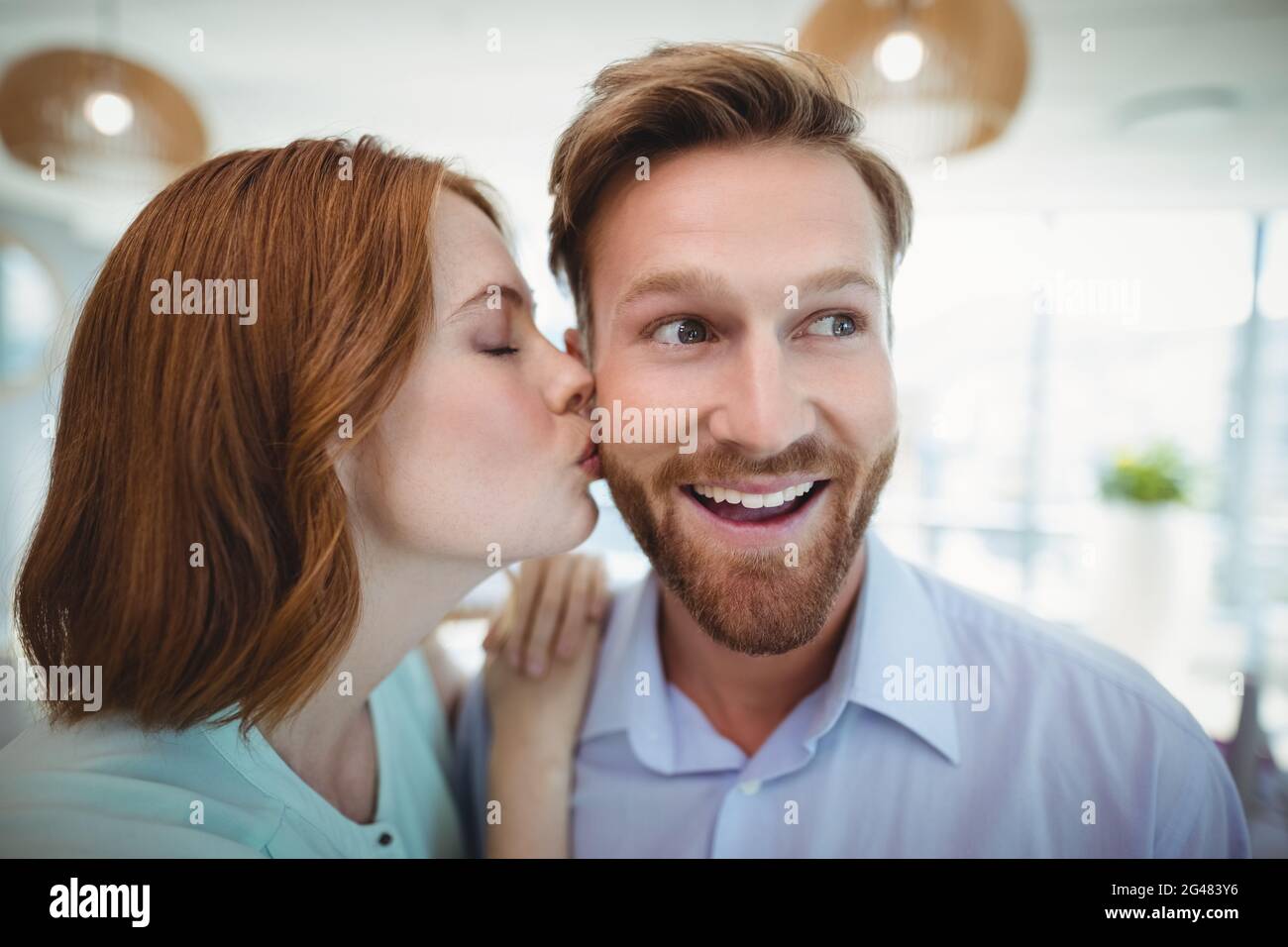Woman kissing male colleague hi-res stock photography and images - Alamy