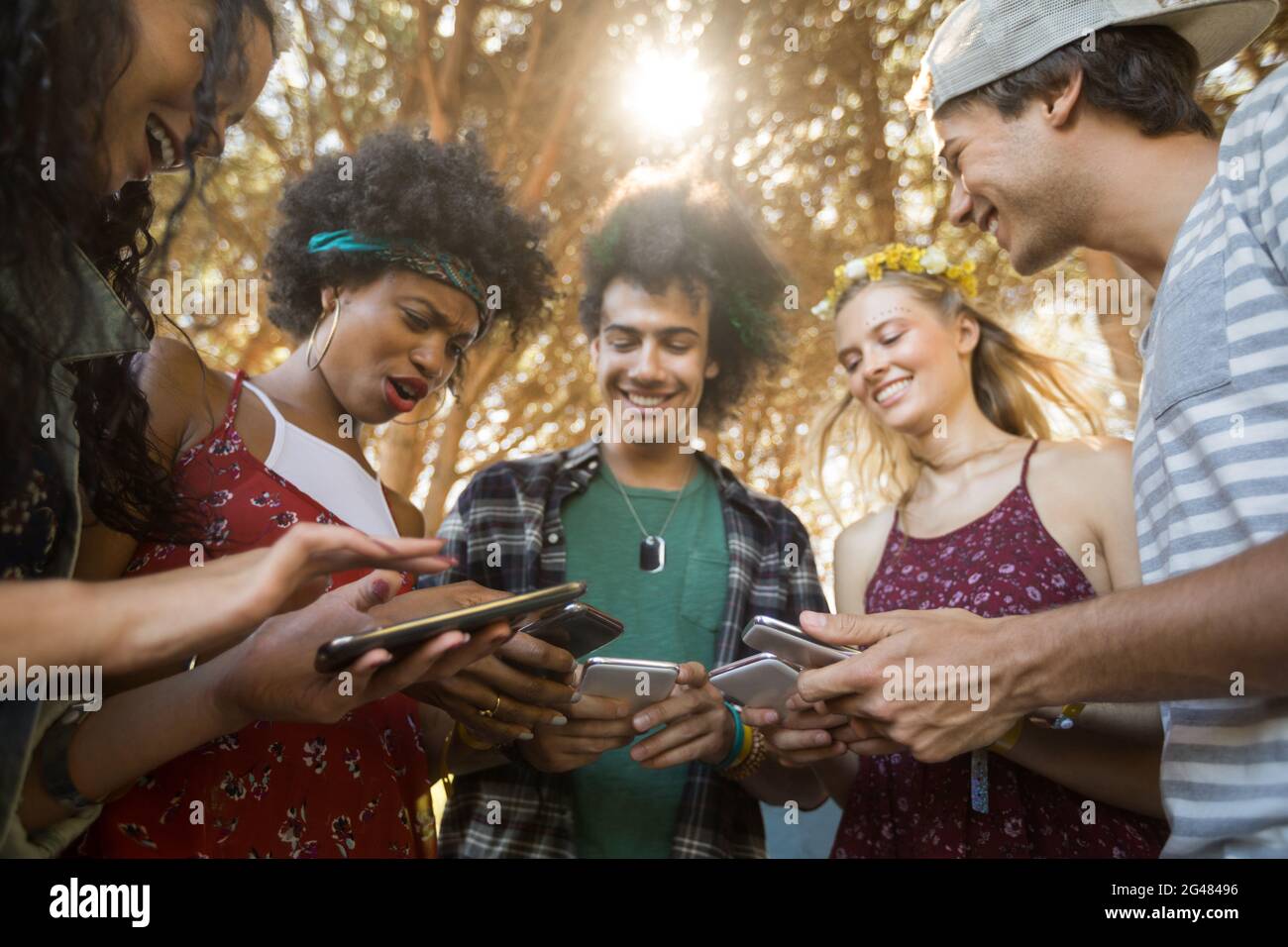 Happy friends using mobile phones together at campsite Stock Photo - Alamy