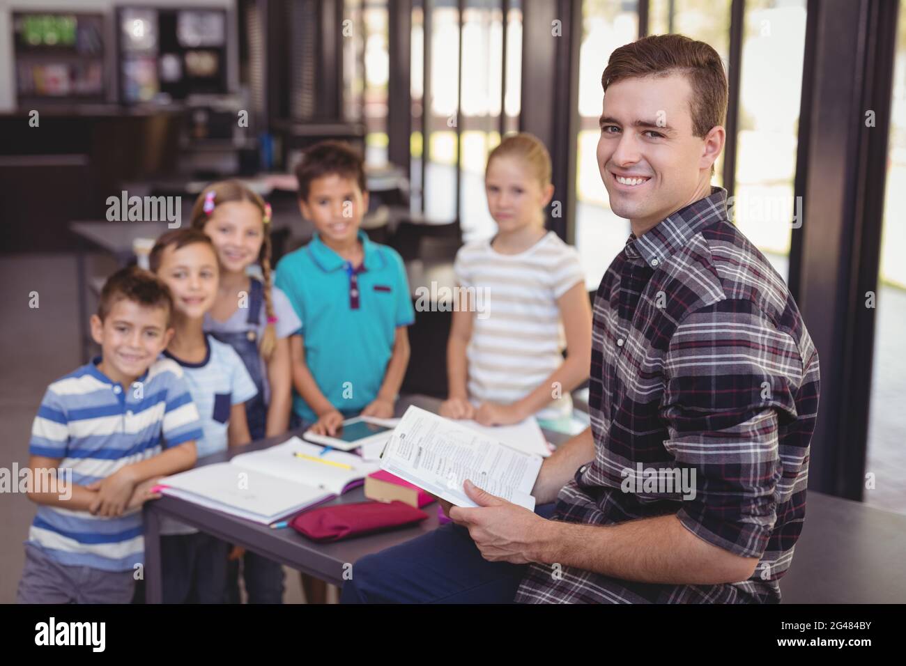 Portrait of teacher teaching schoolkids in library Stock Photo - Alamy