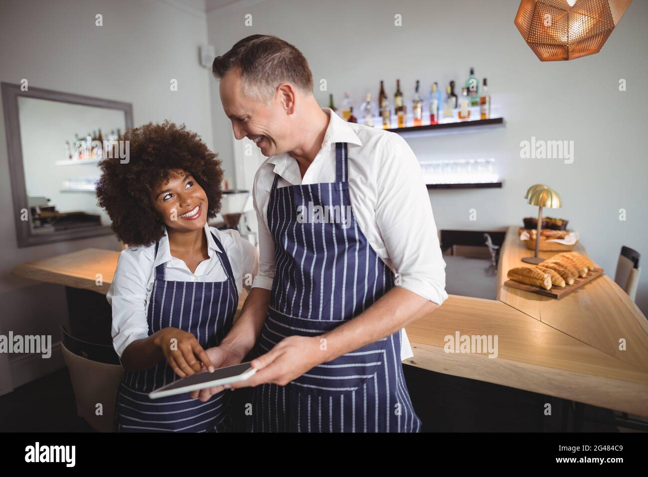 Waiter and waitress using digital tablet at counter Stock Photo - Alamy