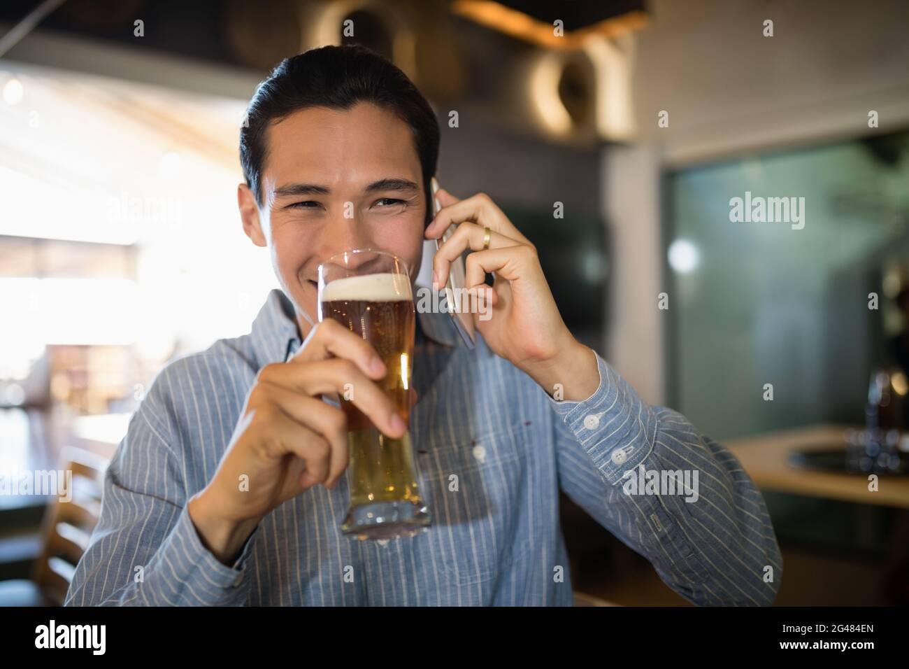 Man having beer while talking on mobile phone Stock Photo - Alamy