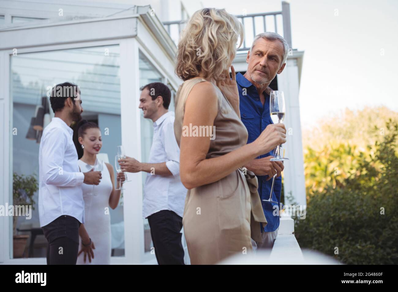 Friends interacting while having champagne in balcony Stock Photo - Alamy