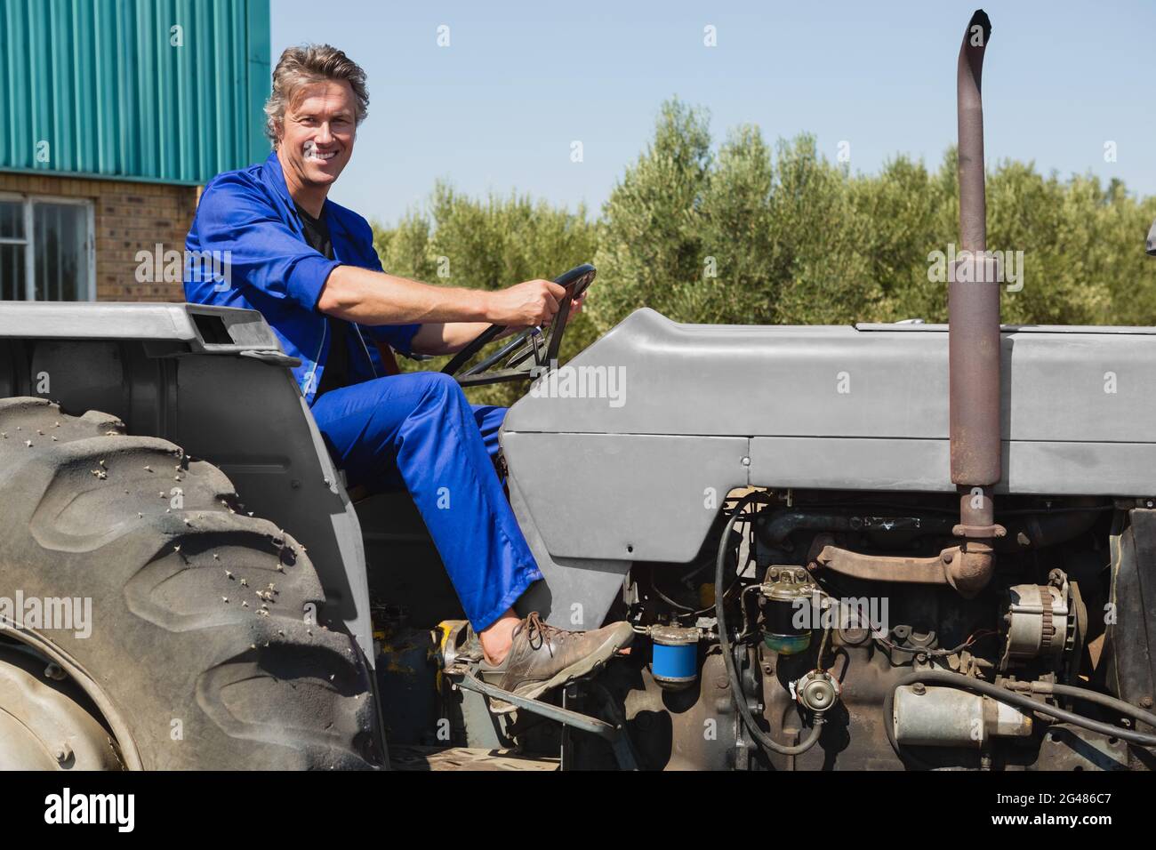 Smiling worker driving a tractor Stock Photo - Alamy