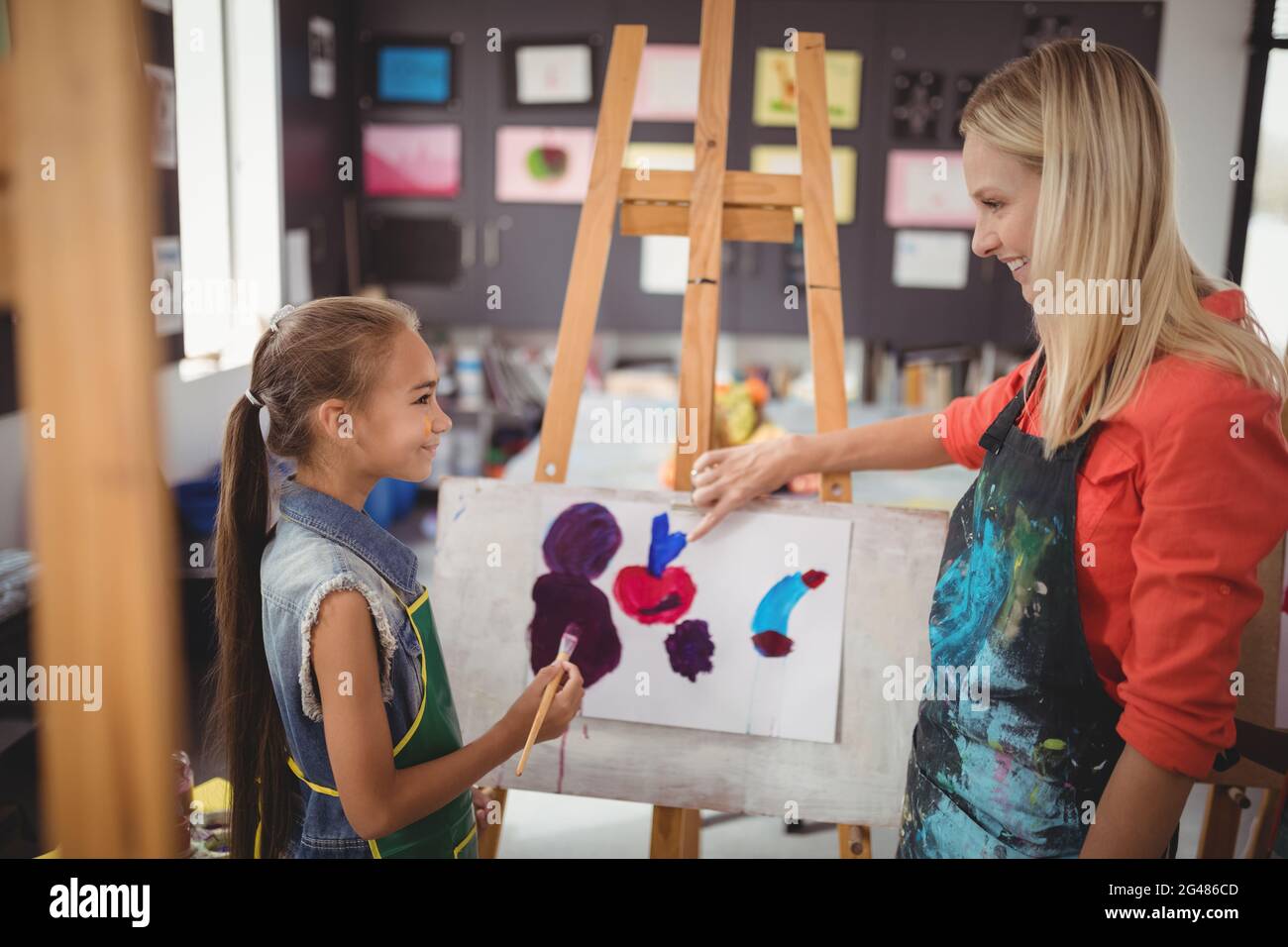 Teacher assisting girl in drawing class Stock Photo - Alamy