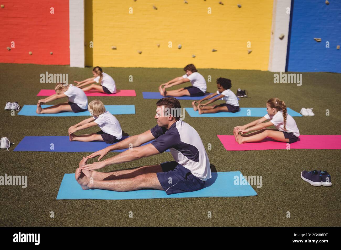 Coach teaching exercise to school kids Stock Photo - Alamy