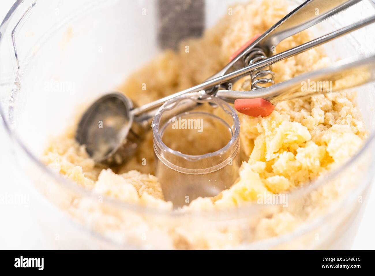 Scooping dough with dough scoop and after rolling in coconut flakes to ...