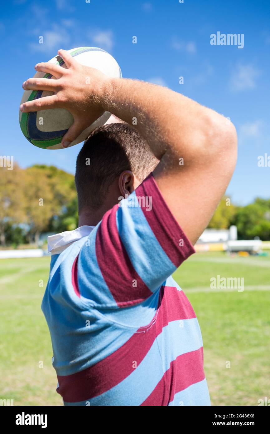 Side view of rugby player throwing ball at field Stock Photo - Alamy